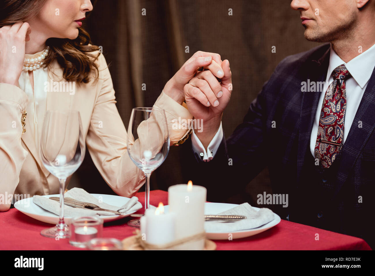 cropped view of couple holding hands during romantic date in restaurant ...