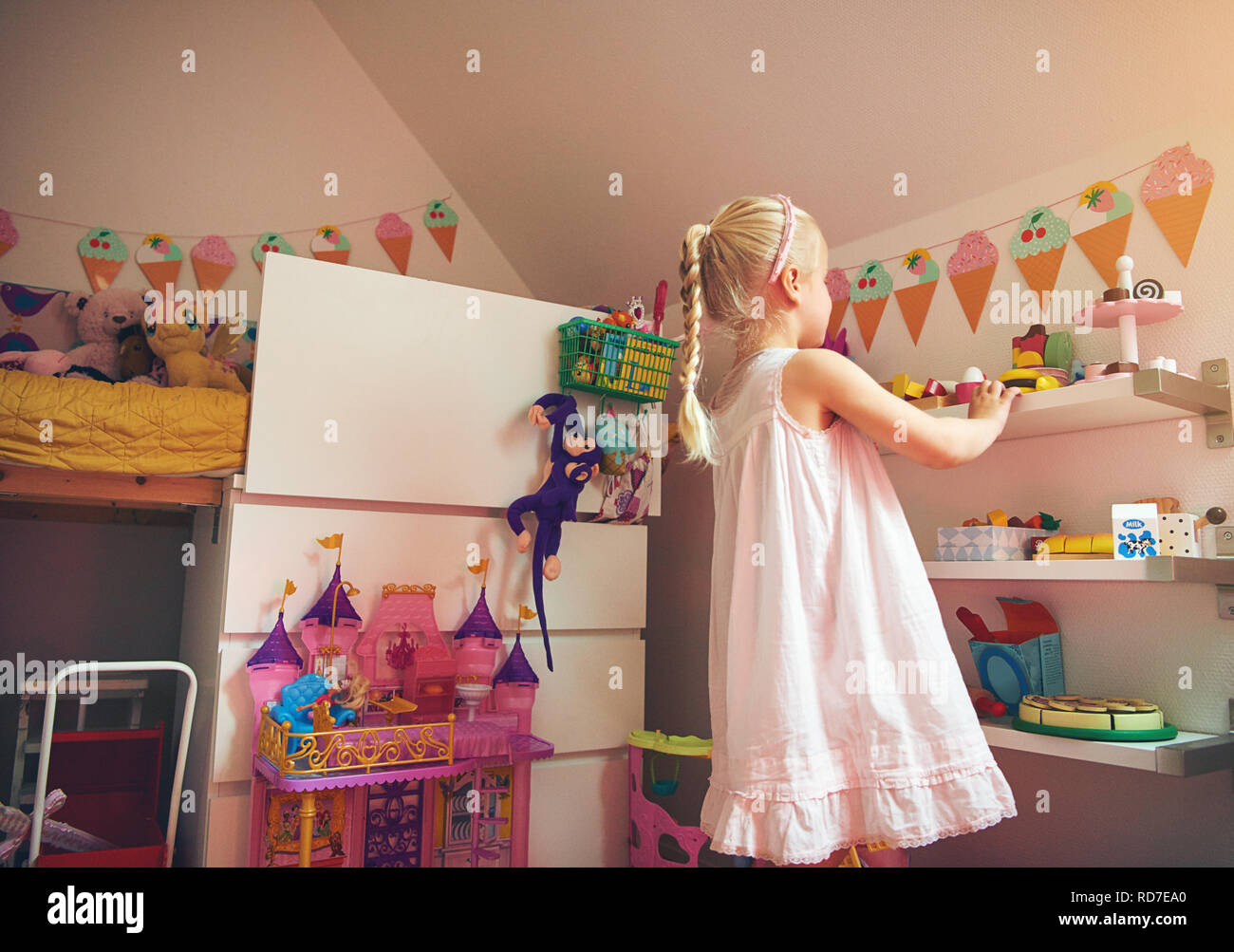 Back view of little girl putting her toys on board. Horizontal indoors ...