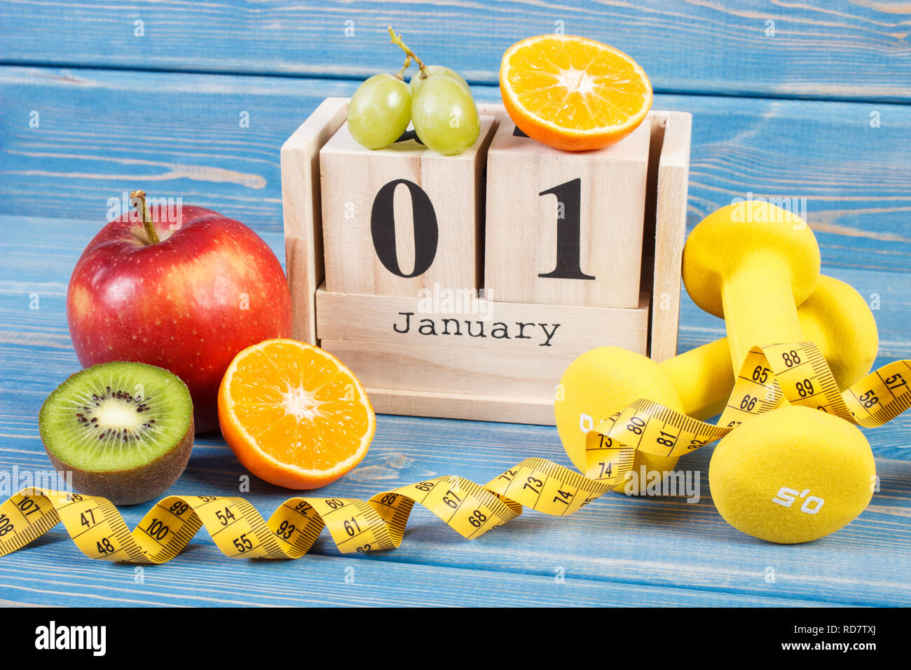 January 1 on cube calendar, fresh ripe fruits, dumbbells and tape ...