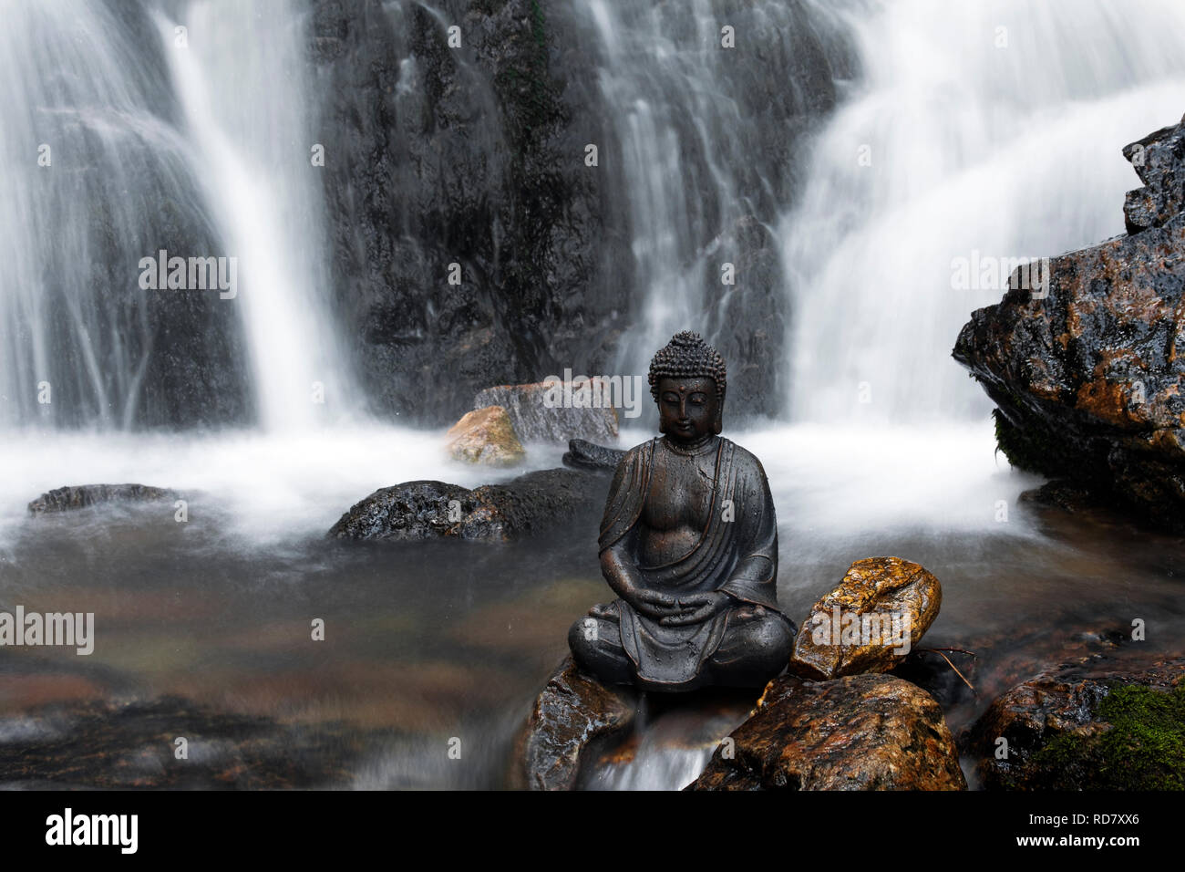 sitting Buddha statue in front of a waterfall Stock Photo - Alamy