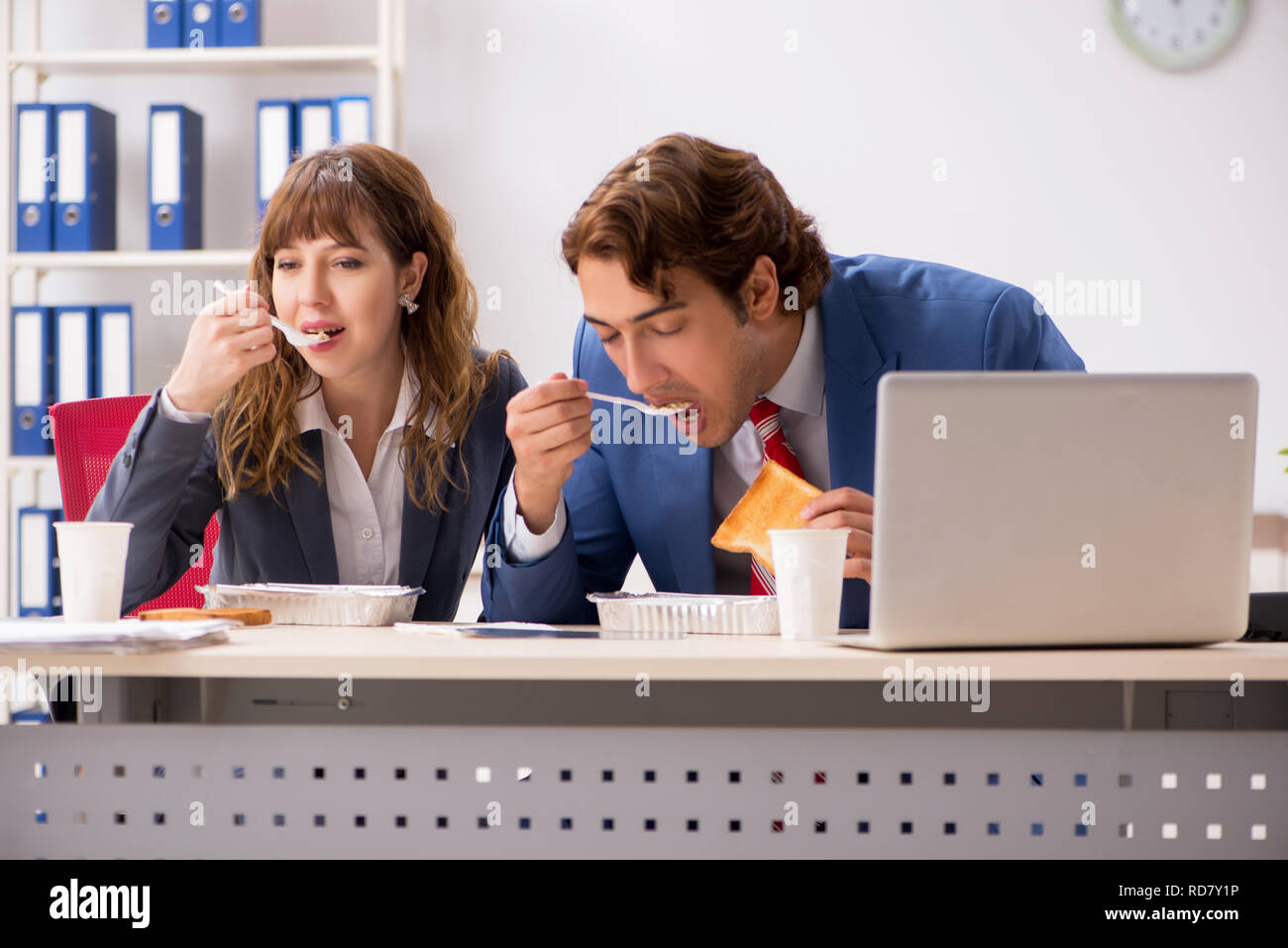 Two colleagues having lunch break at workplace Stock Photo - Alamy