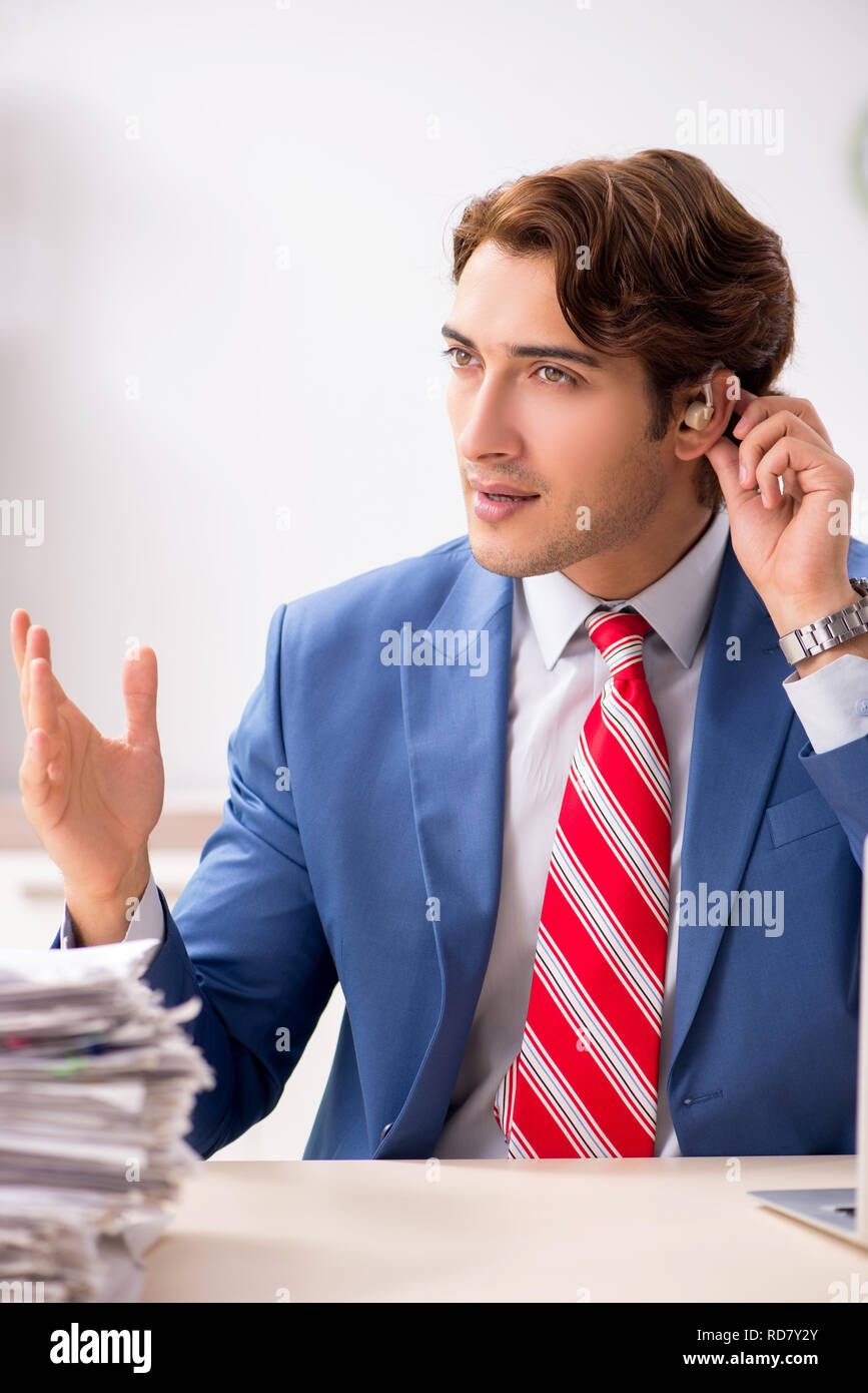 Deaf employee using hearing aid in office Stock Photo - Alamy