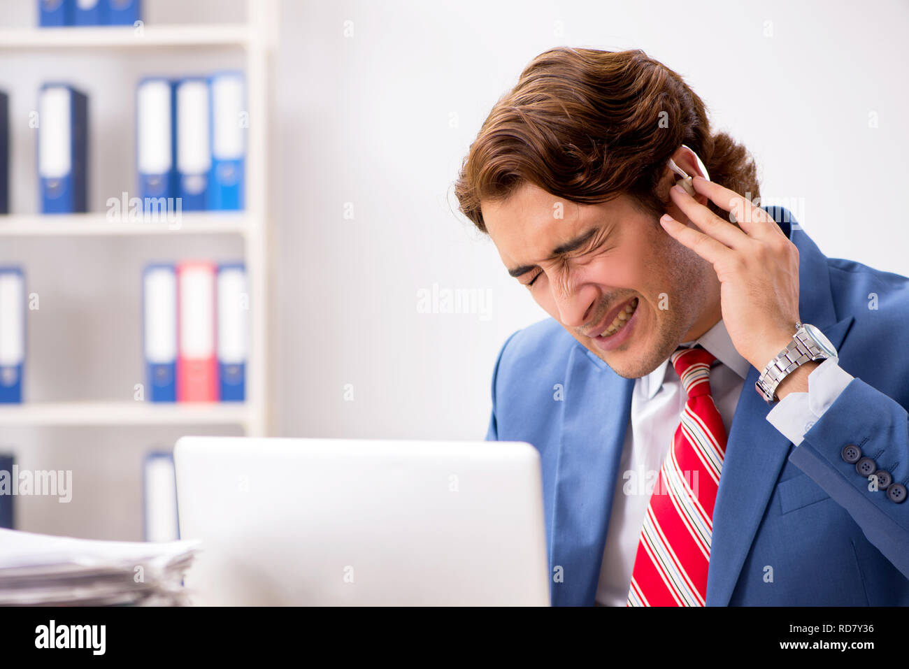 Deaf employee using hearing aid in office Stock Photo - Alamy