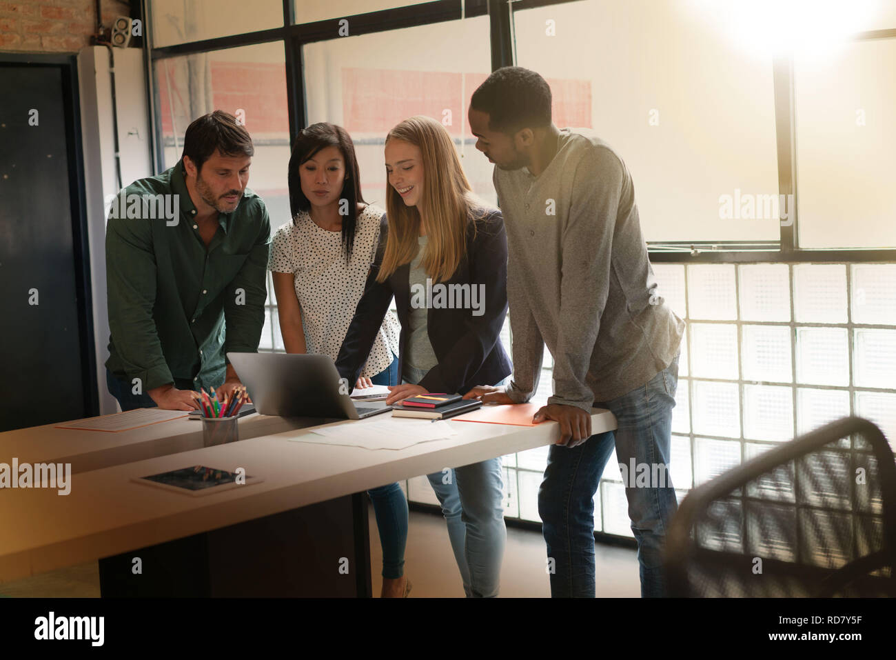 Four attractive co workers standing over desk going through ...