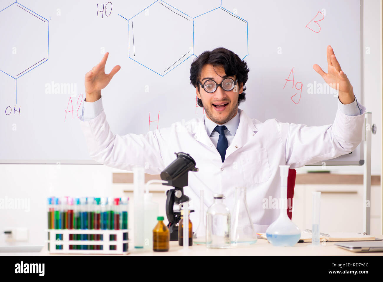 Young funny chemist in front of white board Stock Photo - Alamy