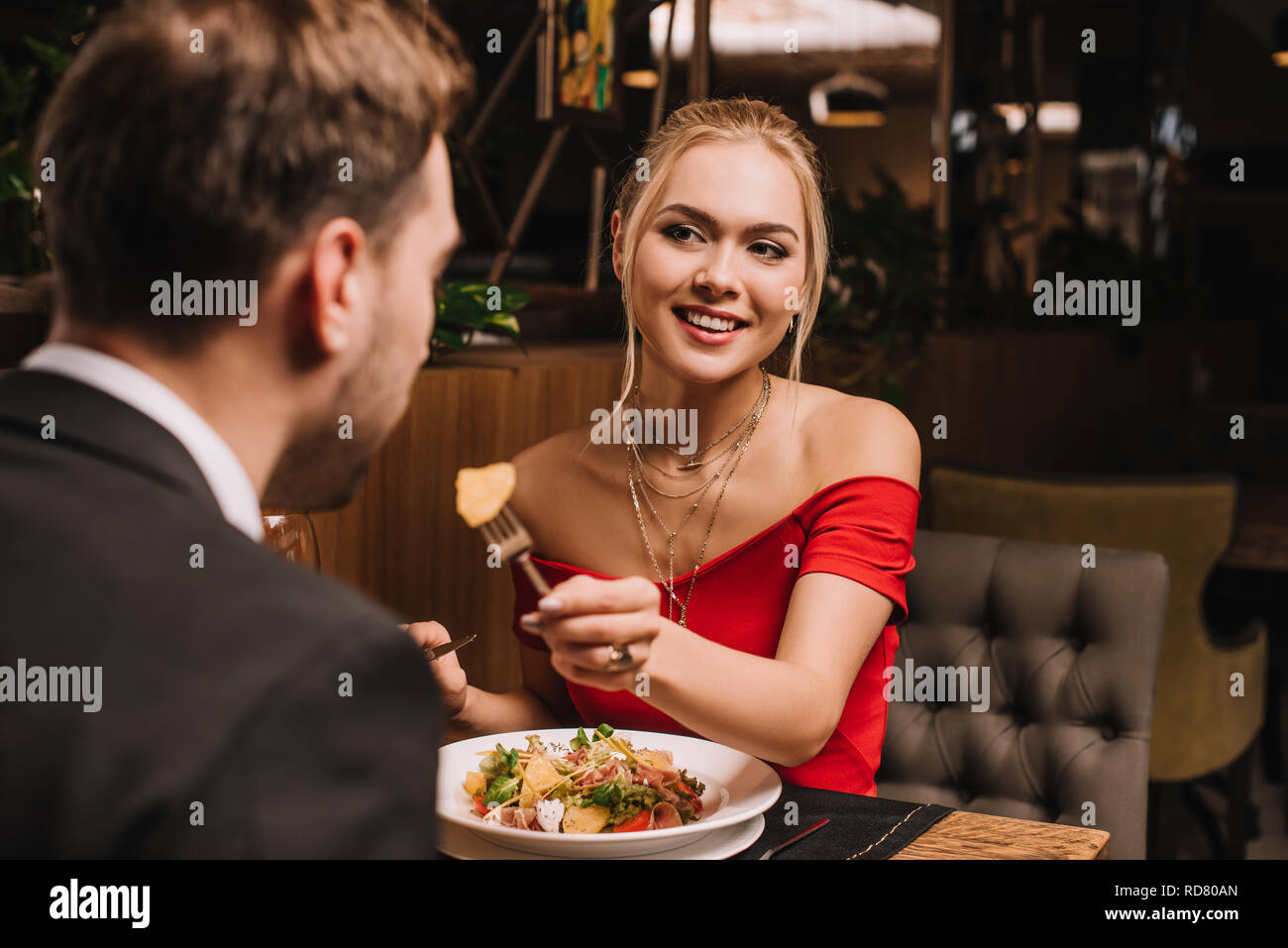 cheerful girlfriend feeding boyfriend in restaurant Stock Photo - Alamy