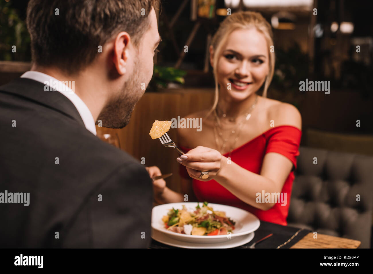 attractive girlfriend feeding boyfriend in restaurant Stock Photo - Alamy