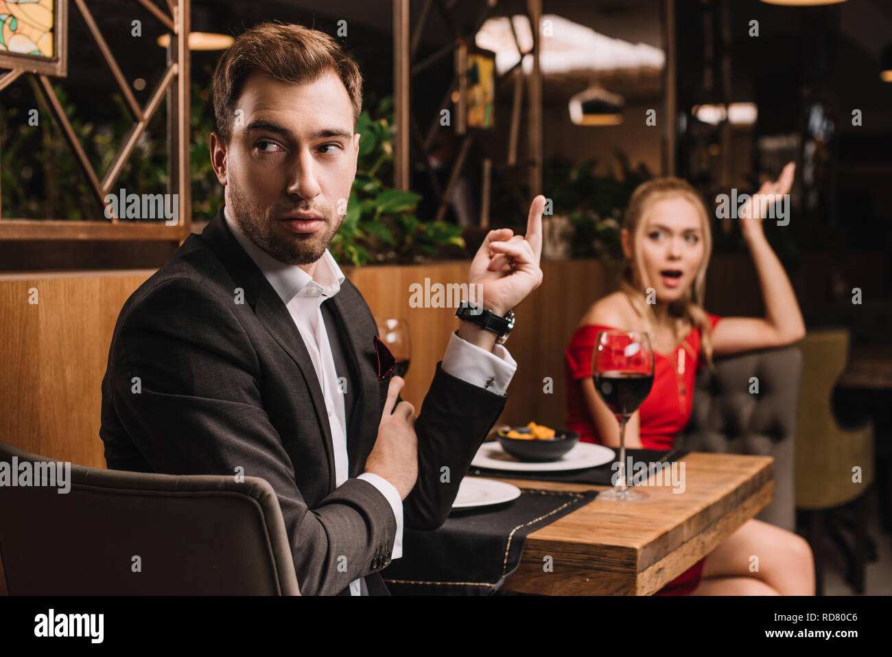 selective focus of offended man showing middle finger to shocked ...