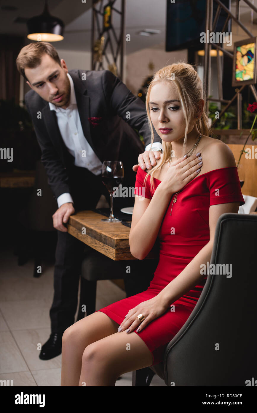selective focus of blonde woman sitting upset near worried boyfriend in ...