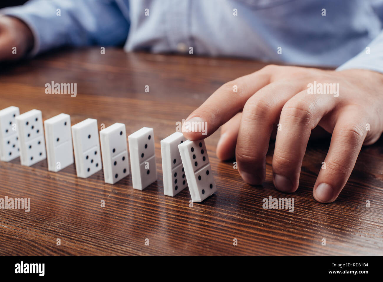 partial view of man pushing domino row on wooden desk Stock Photo - Alamy