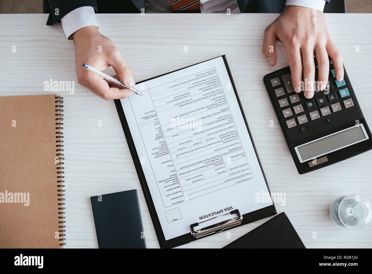top view of man counting on calculator while holding pen near document ...
