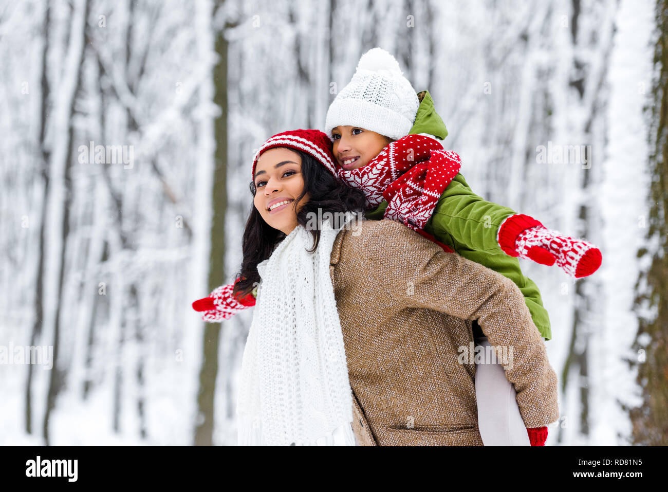 attractive african american woman giving piggyback ride to smiling ...