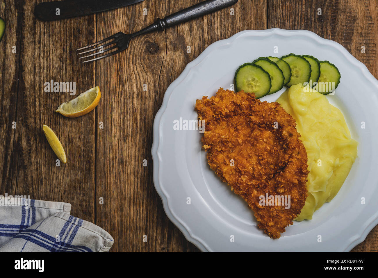 Chicken fried schnitzel with mashed potatoes and lemon on wood table ...