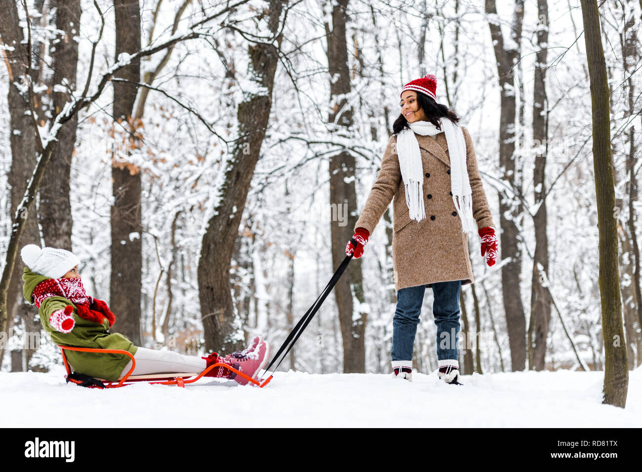 attractive african american woman pulling preteen daughter on sledge ...