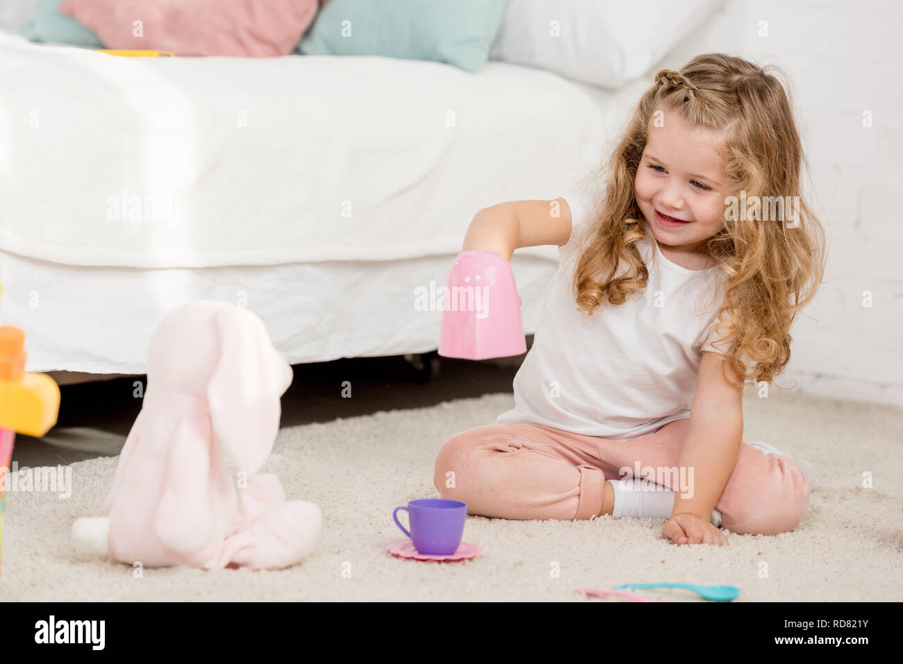 adorable happy kid playing with rabbit toy and plastic cups in children ...