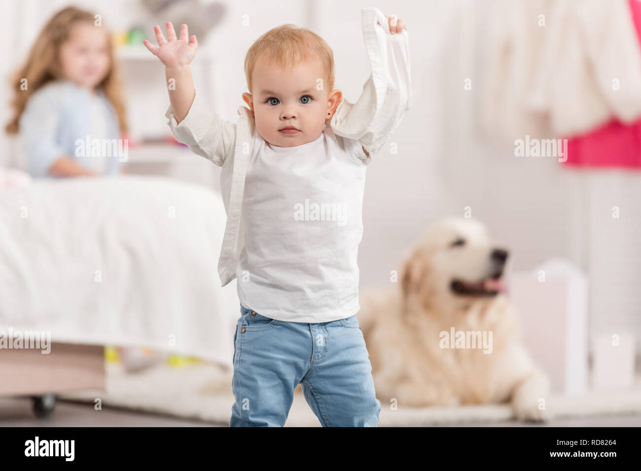 funny adorable kid standing with raised hands and looking at camera in ...