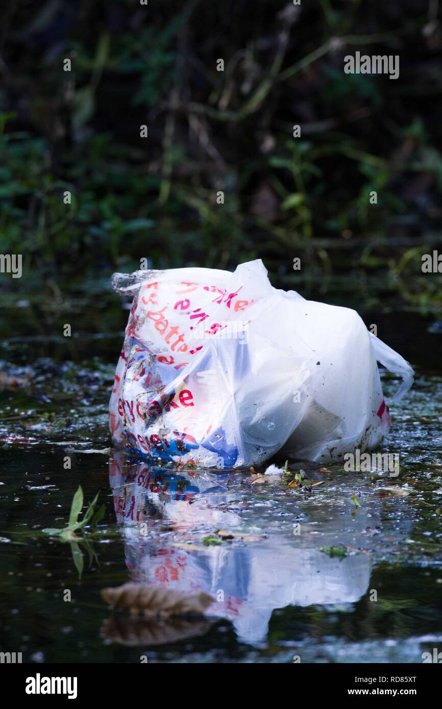 Bag of litter floating in river in town discarded Stock Photo - Alamy