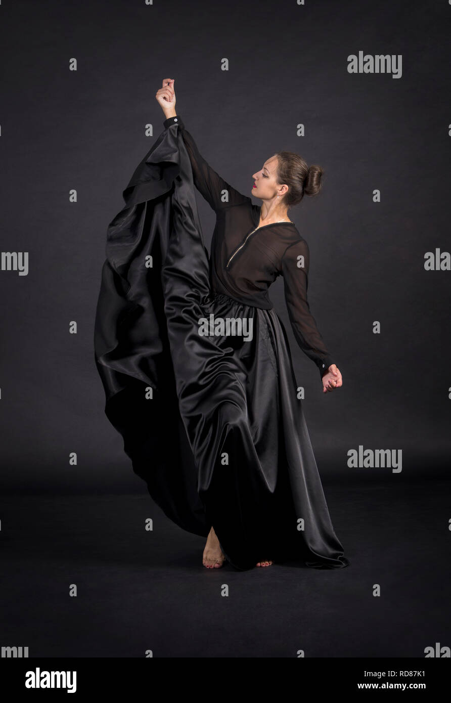 A Young, smiling woman in black suit dancing modern choreography.Studio ...