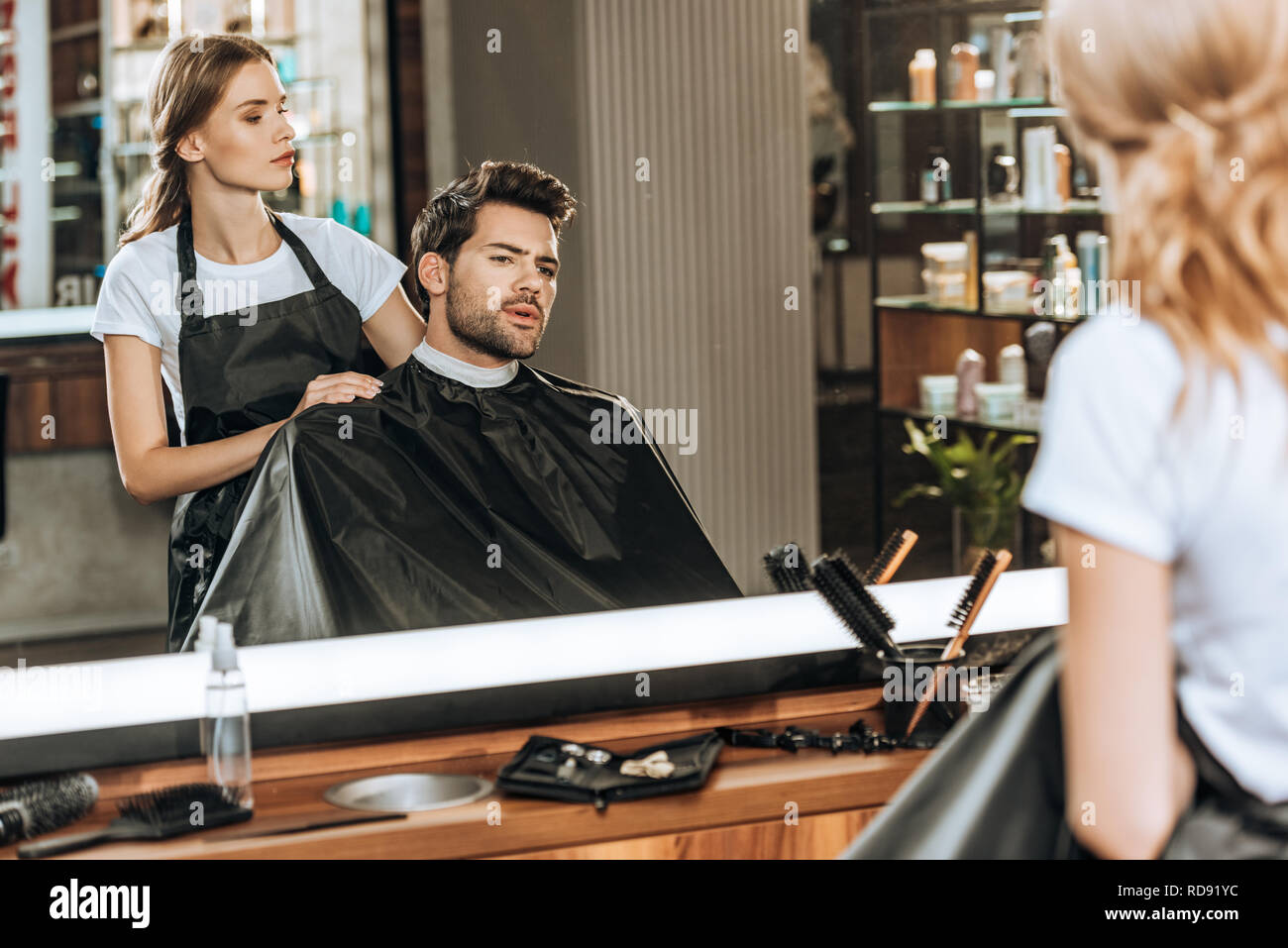 female hairstylist cutting hair to handsome young man in beauty salon ...