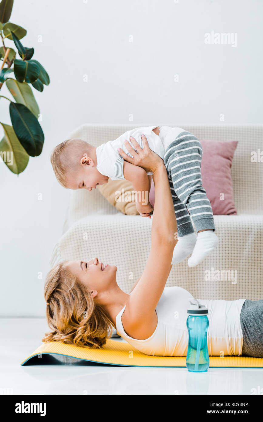 woman lying near plant and raising adorable child above head Stock ...