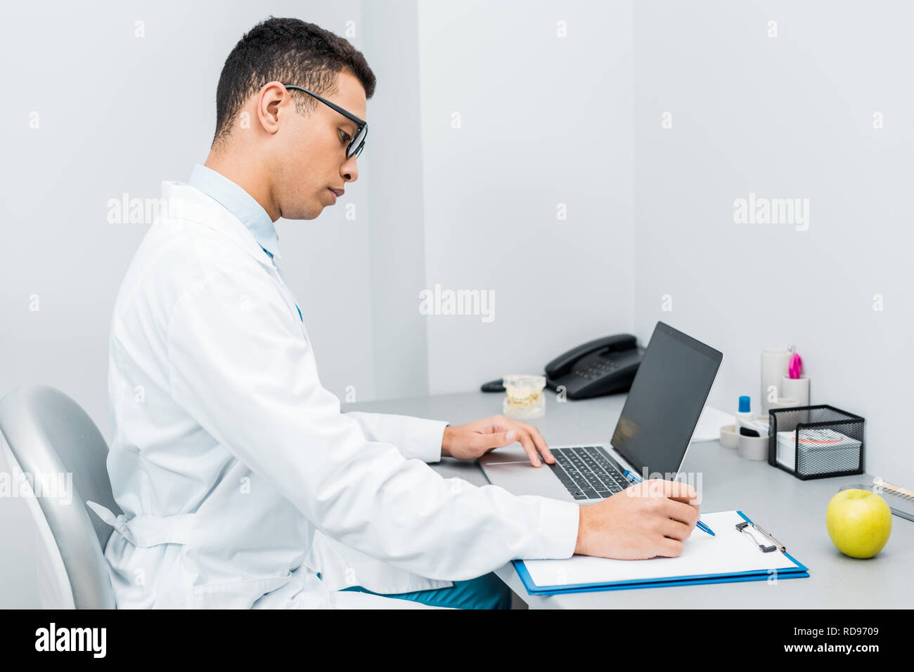 handsome african american doctor making notes and using laptop Stock ...