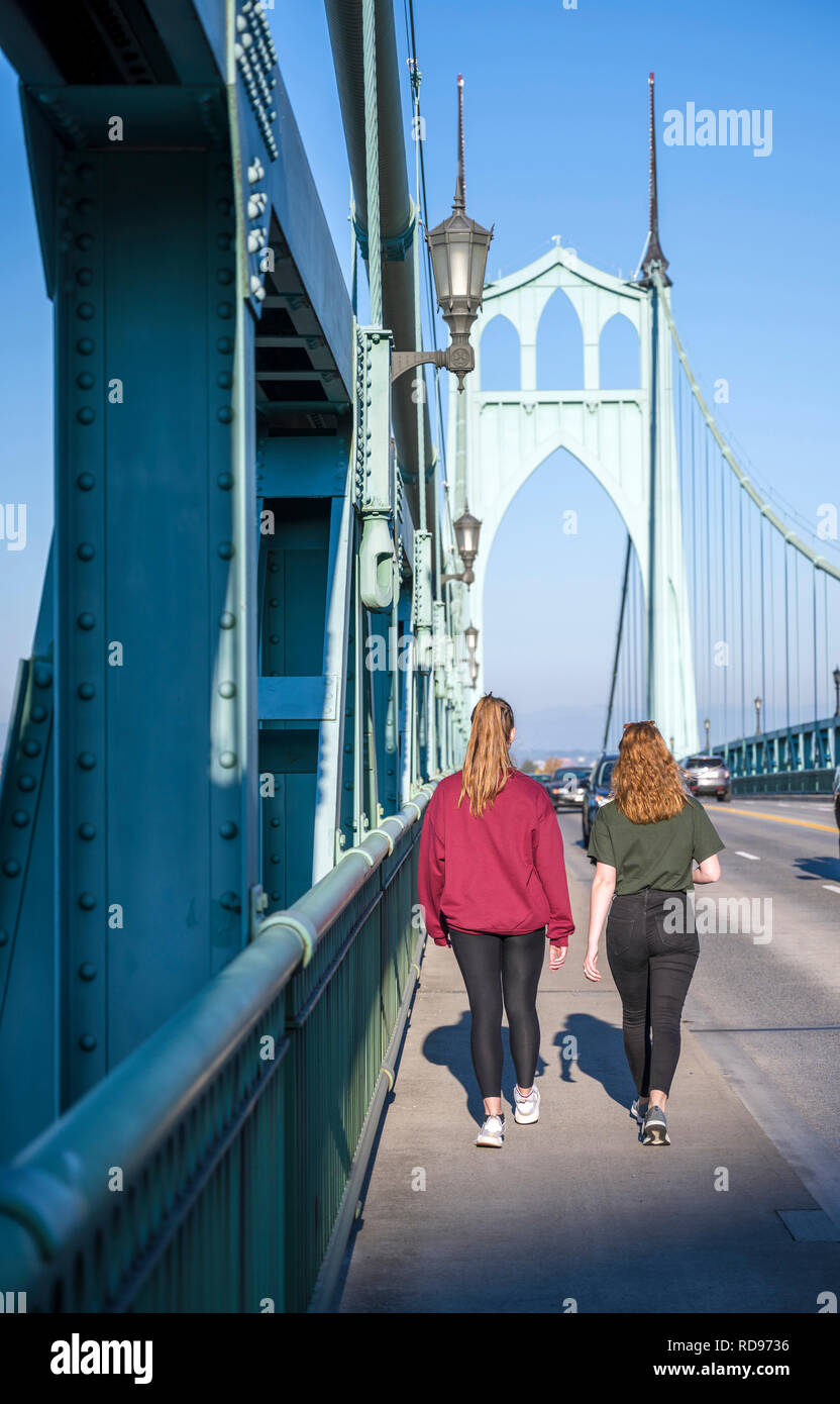 Two young girls with a good fit and long hair walking along the walkway ...