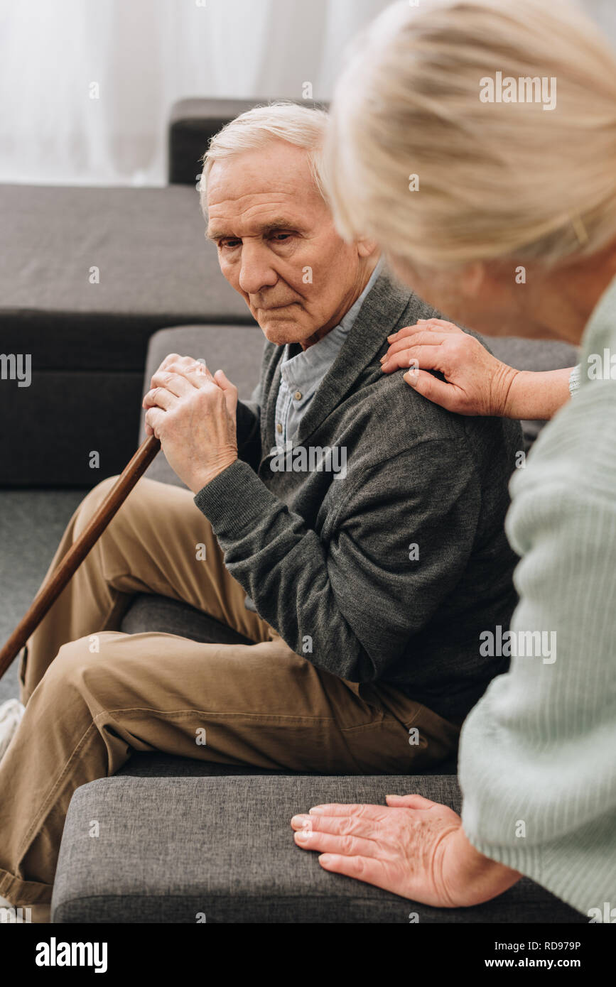 sad retired husband with walking cane sitting in living room near ...