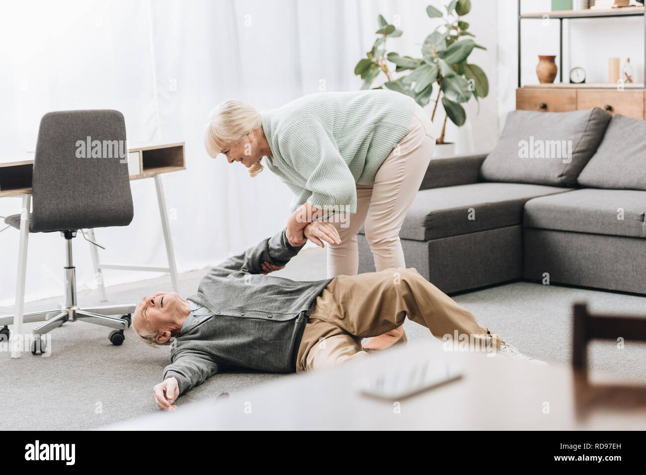 old woman helping to husband who falled down on floor Stock Photo - Alamy