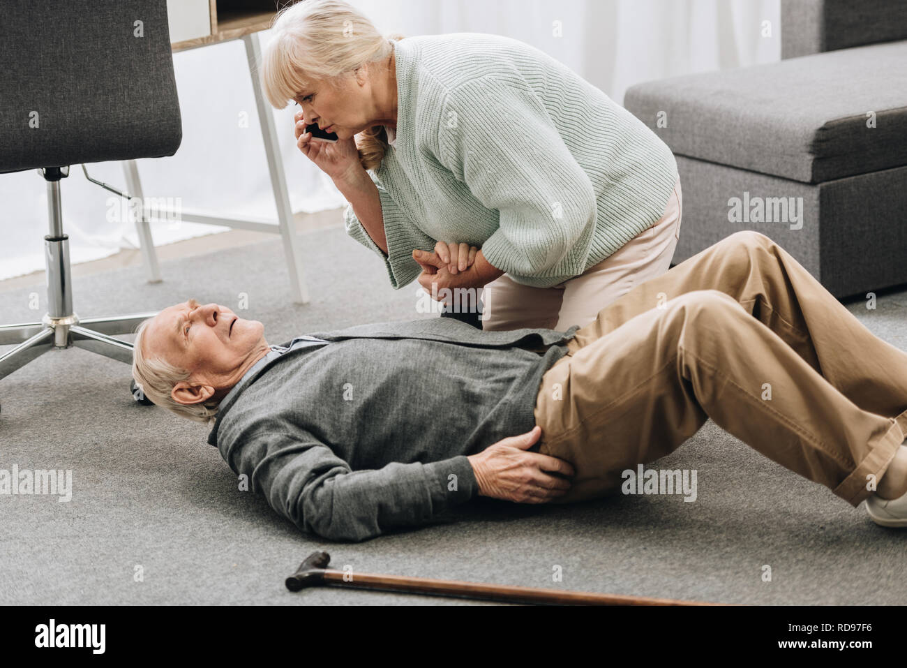 senior woman looking at husband who falled down with heart attack and ...