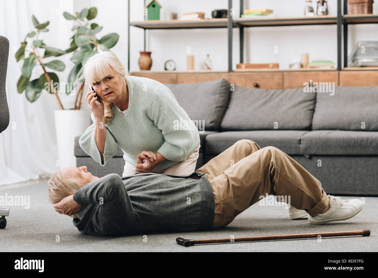 senior woman holding hand of dying old man with walking stick and ...