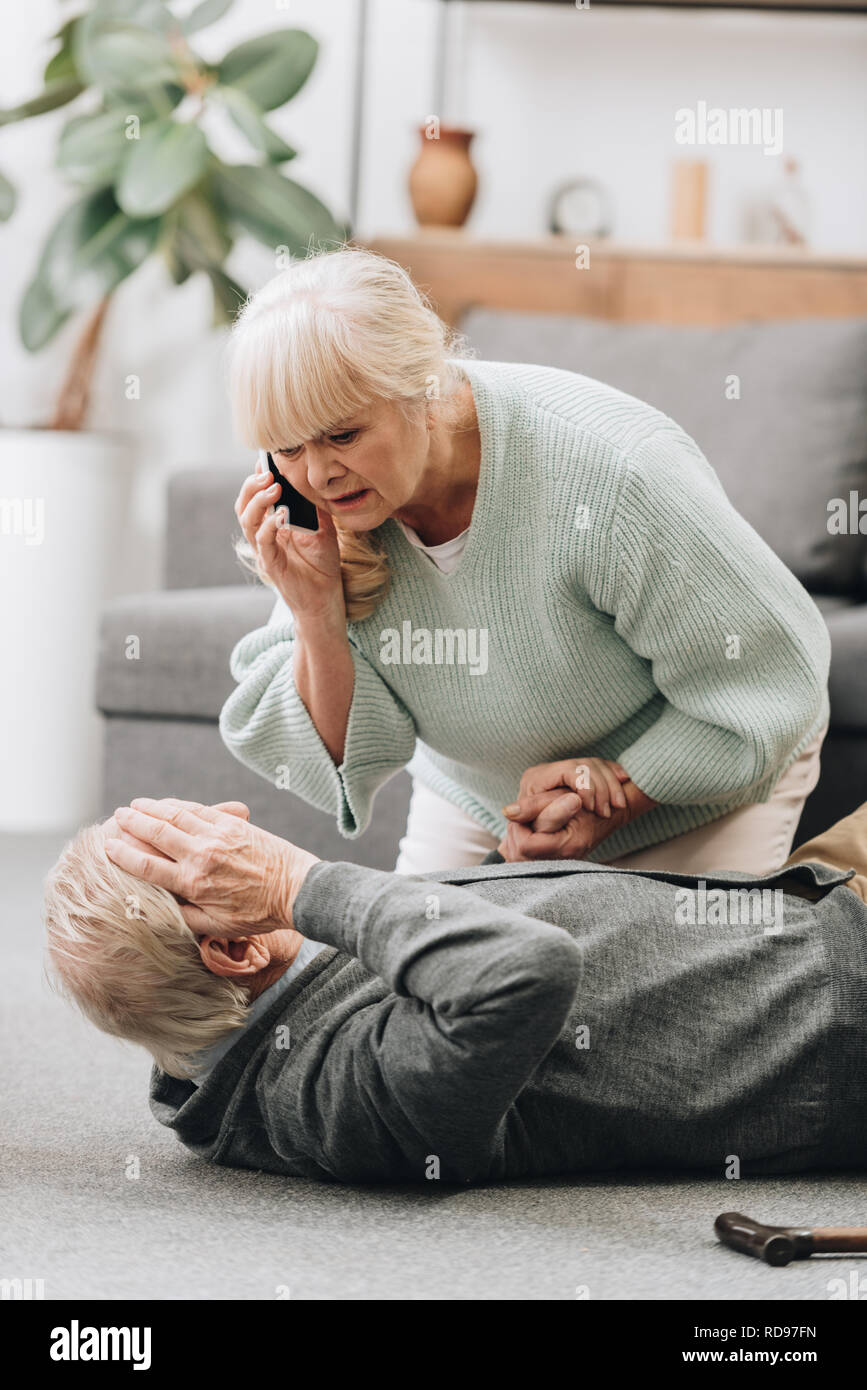 senior woman helping to husband who falled down on floor and holding ...