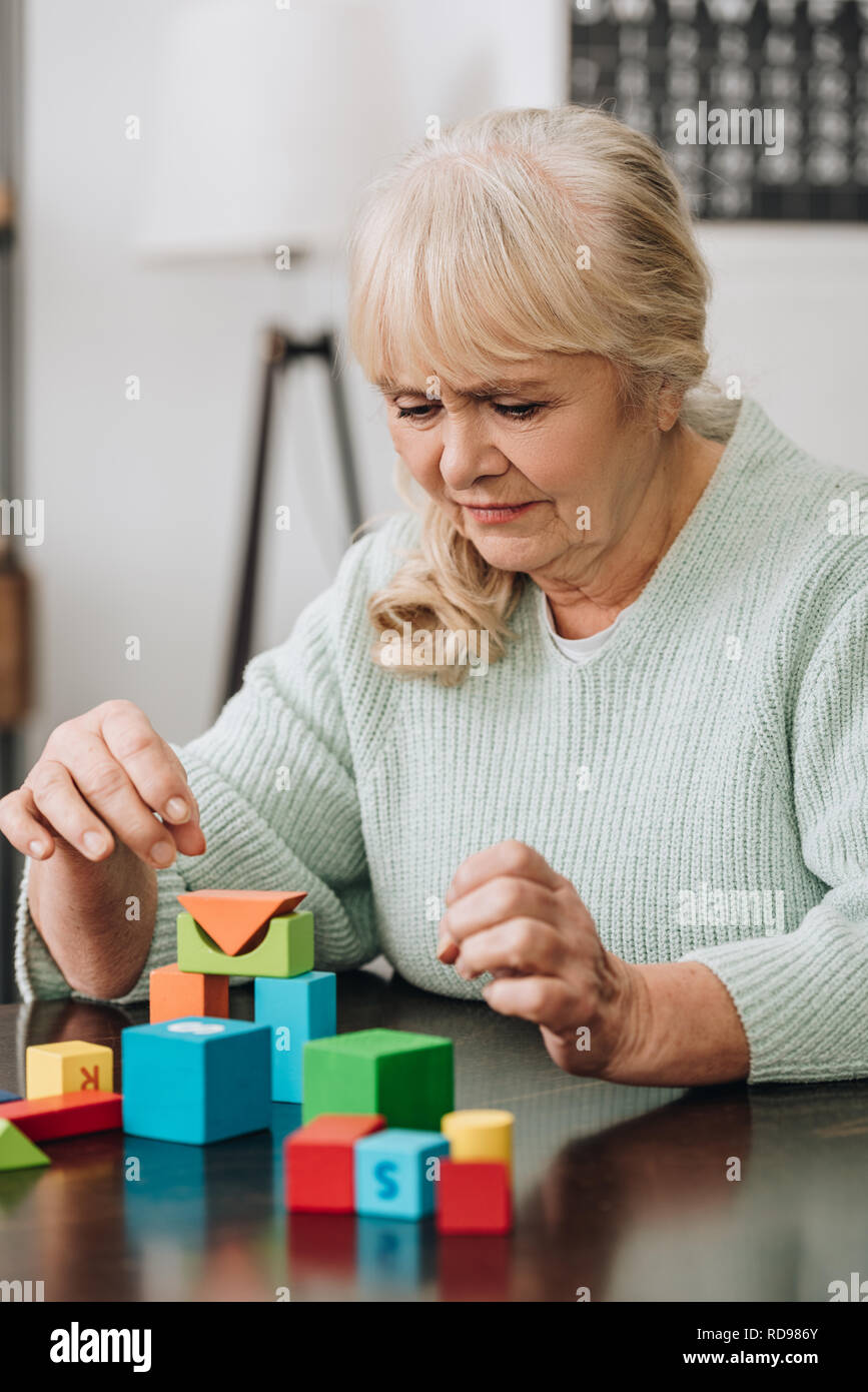 blonde senior woman playing with wooden toys at home Stock Photo - Alamy