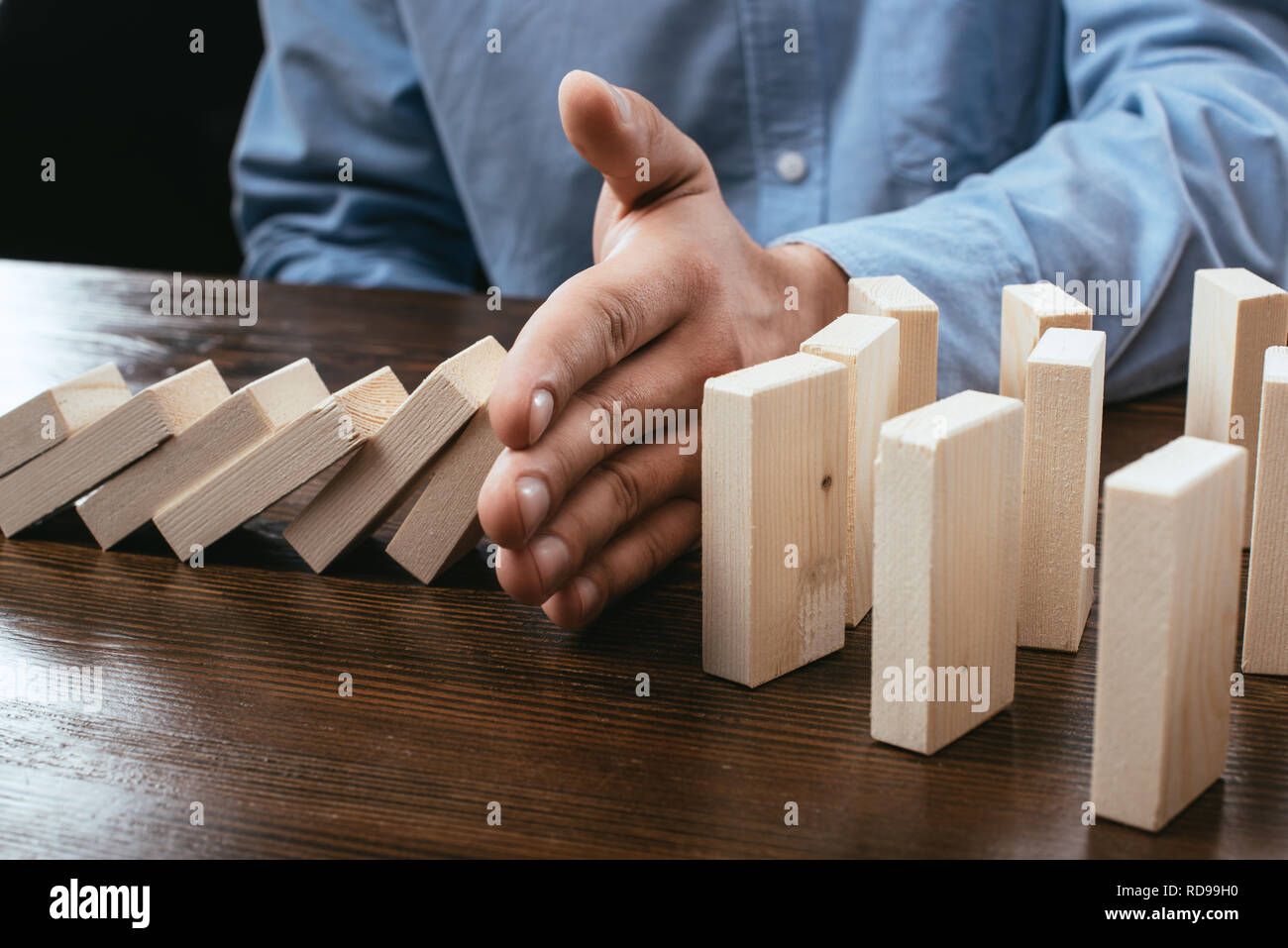 cropped view of man preventing wooden blocks from falling on desk Stock ...