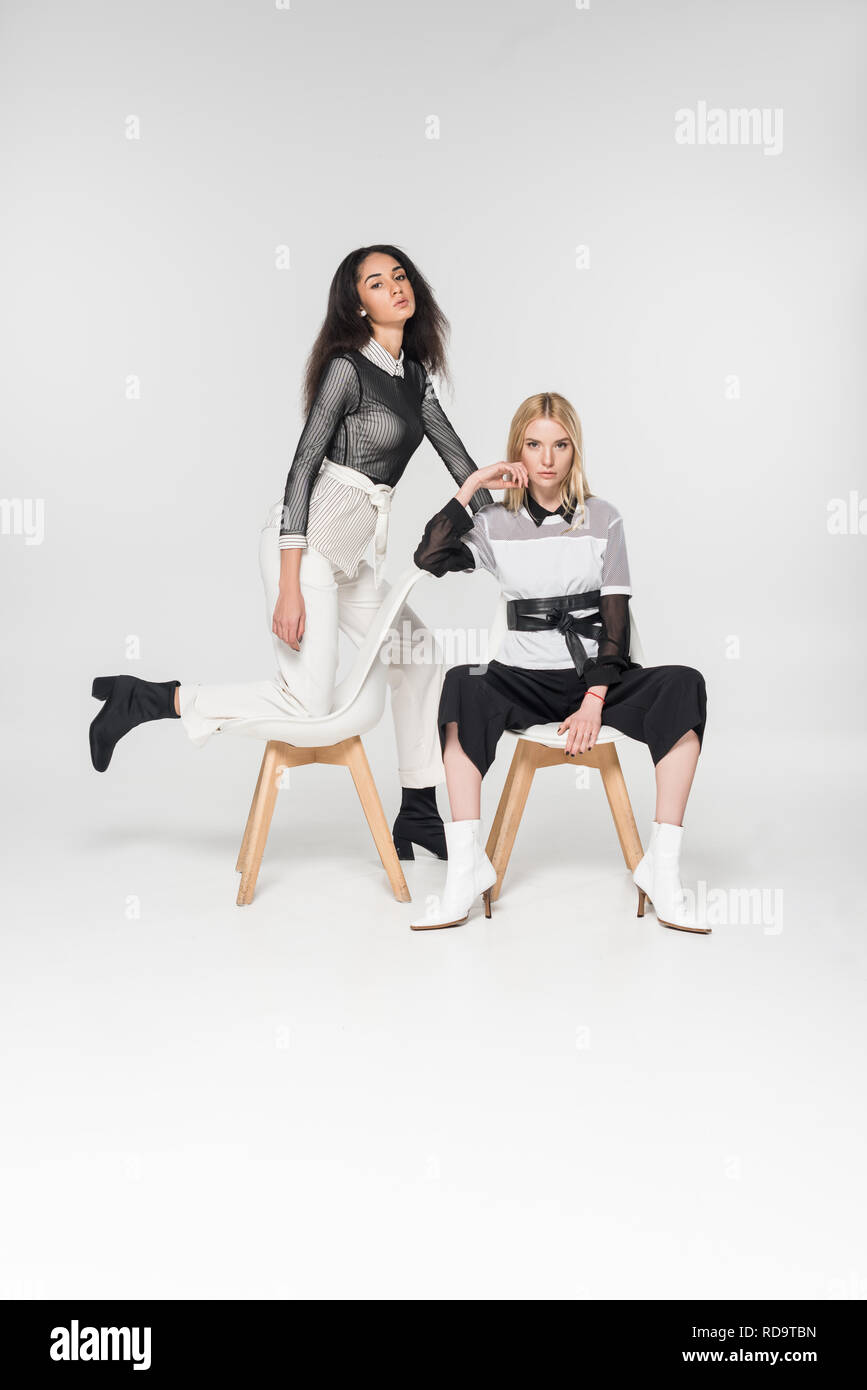 attractive multiethnic female models in black and white clothes sitting ...