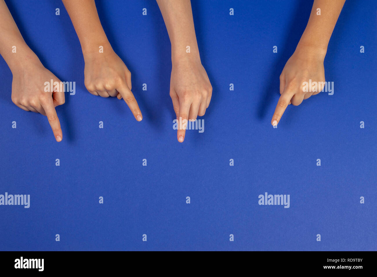 Many kids hands pointing to something on blue background Stock Photo ...