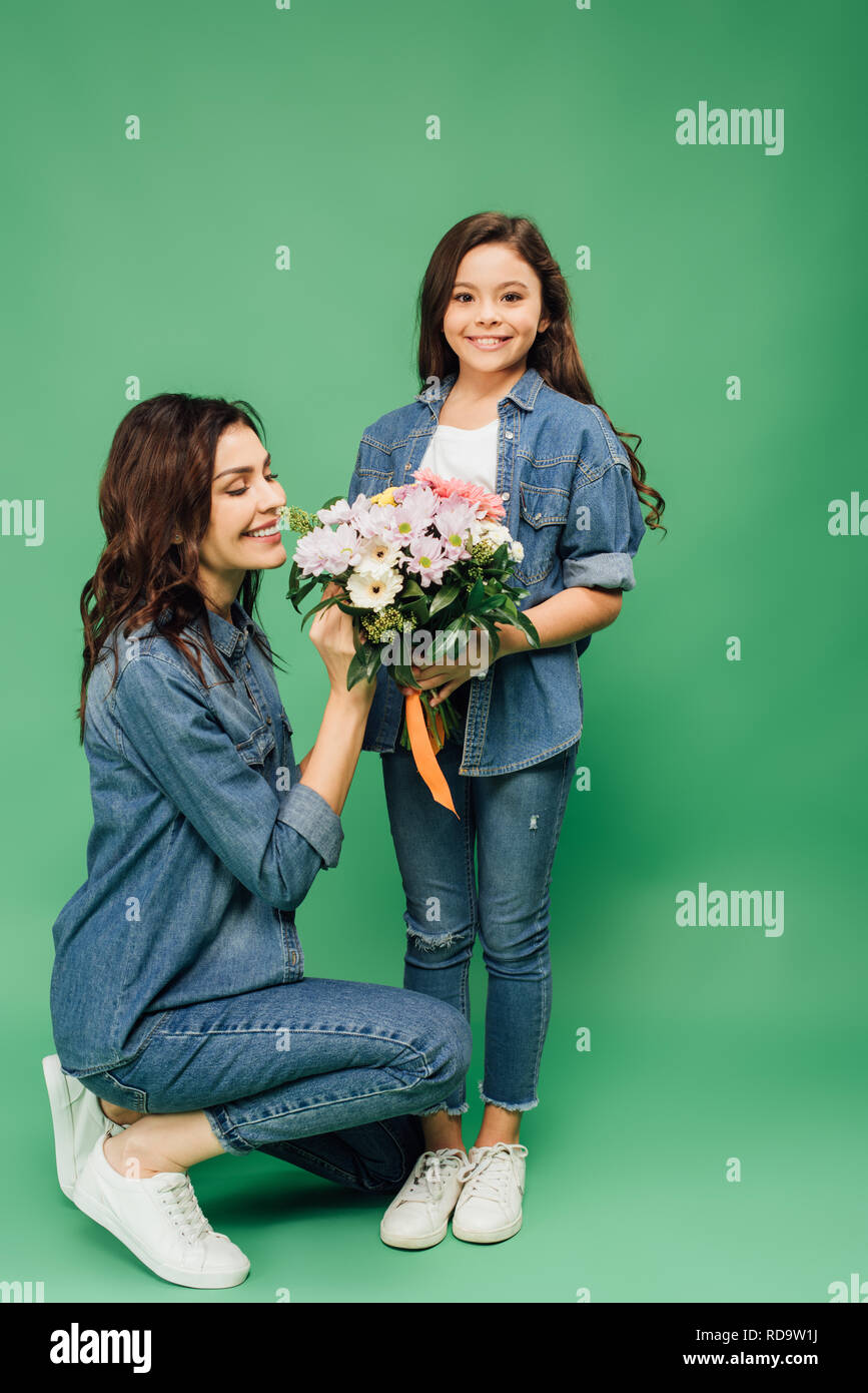 happy daughter presenting flowers to beautiful mother on green ...