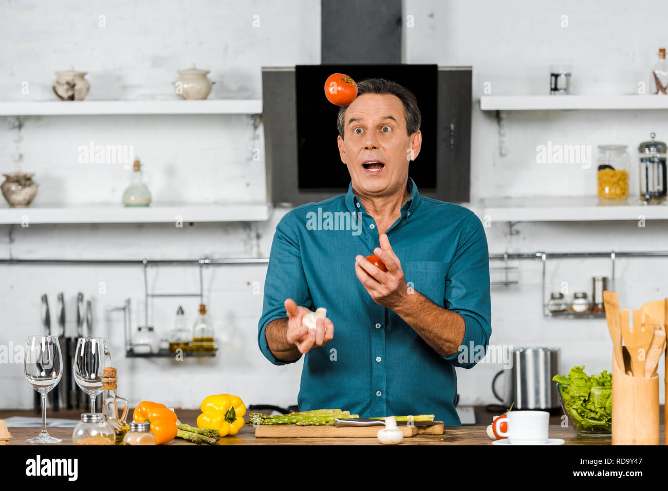 surprised handsome middle aged man juggling vegetables while cooking in ...