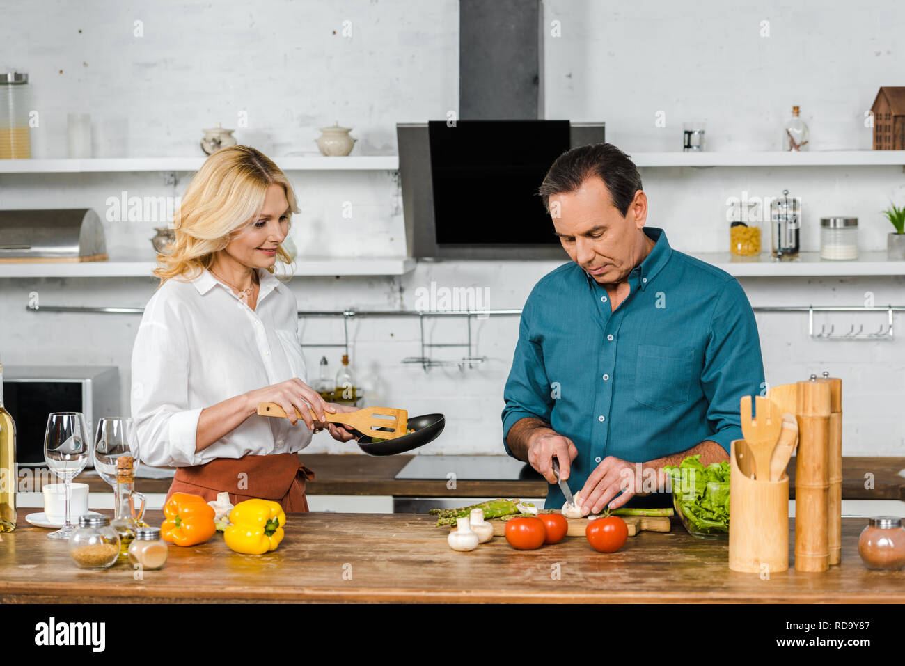 mature wife and husband cooking vegetables together in kitchen Stock ...