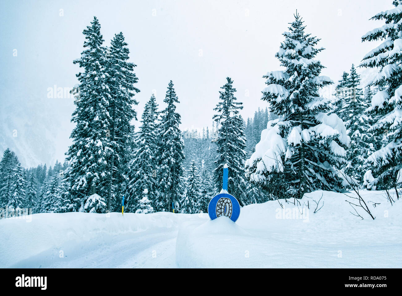 Snow covered street with snow chains sign Stock Photo - Alamy