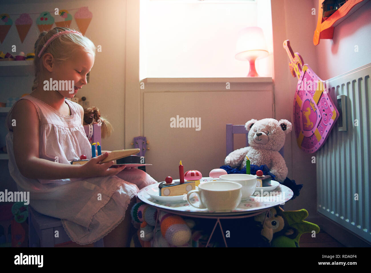 Adorable little girl playing tea-party with bear and toy cake ...