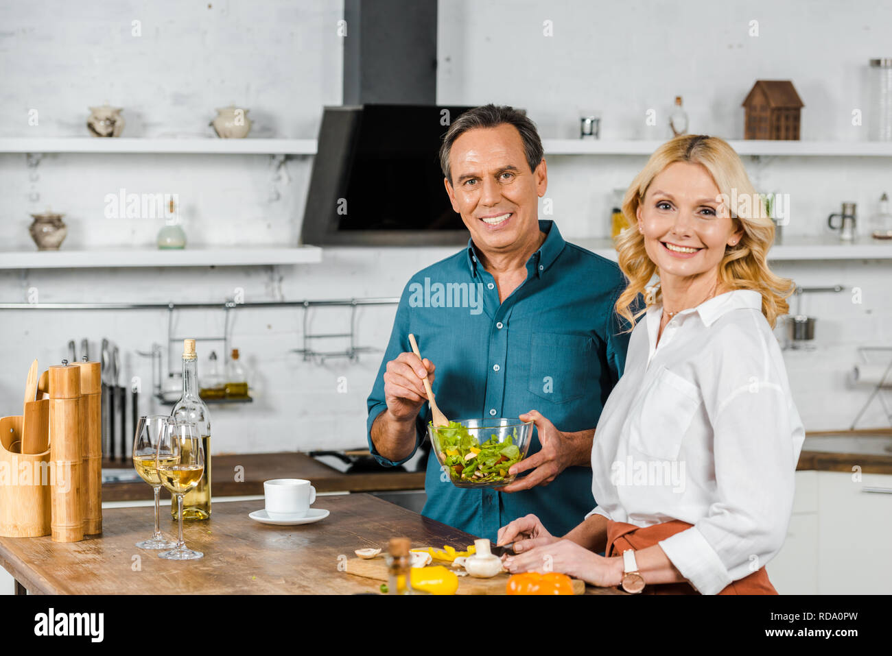 happy mature wife and husband cooking salad together in kitchen ...