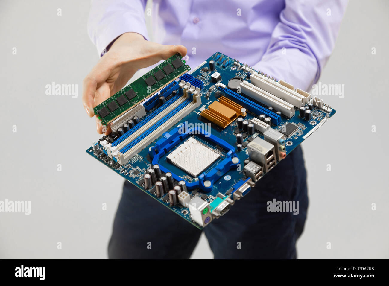 RAM and motherboard in men's hands close-up isolated on light ...