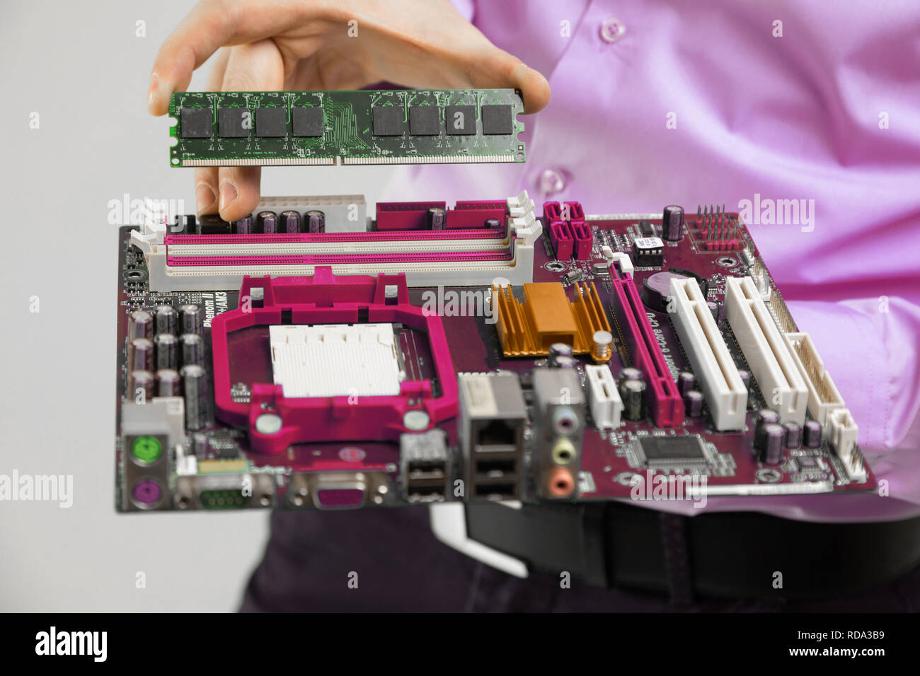 RAM and motherboard in men's hands close-up isolated on light ...