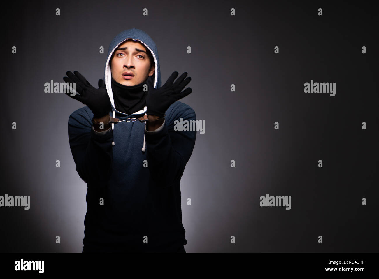 Young gangster in hood on grey background Stock Photo - Alamy