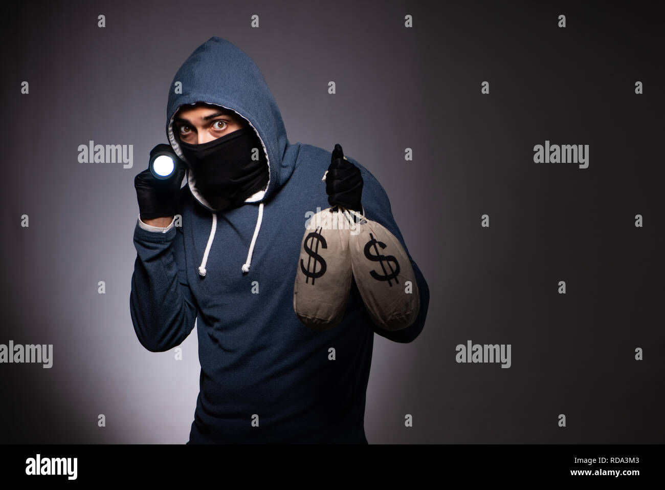 Young gangster in hood on grey background Stock Photo - Alamy