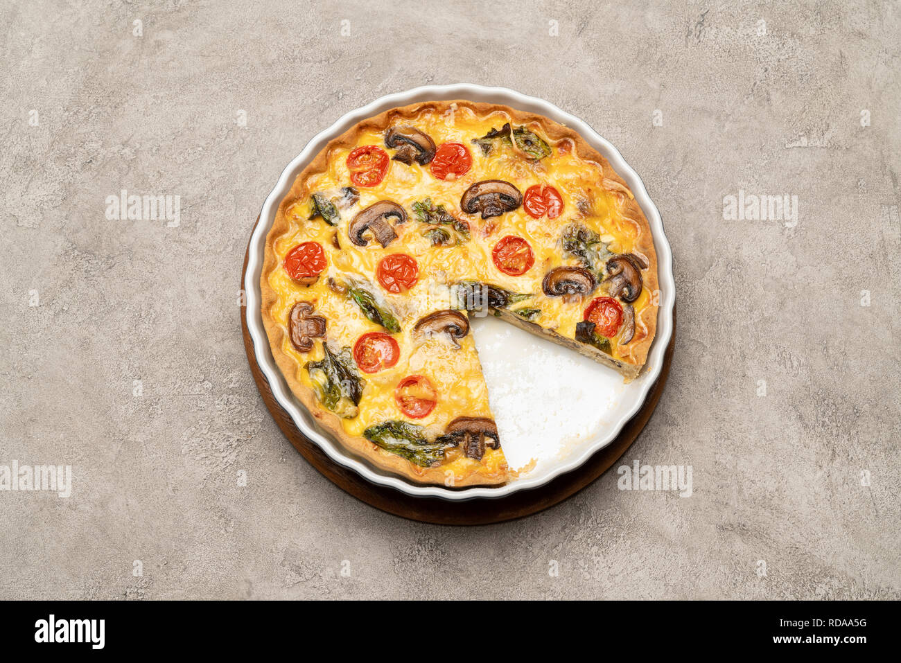 Baked homemade quiche pie in ceramic baking form on concrete background ...