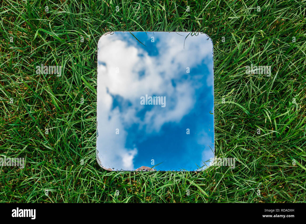 Rectangular mirror reflecting the blue sky with clouds lying on the ...