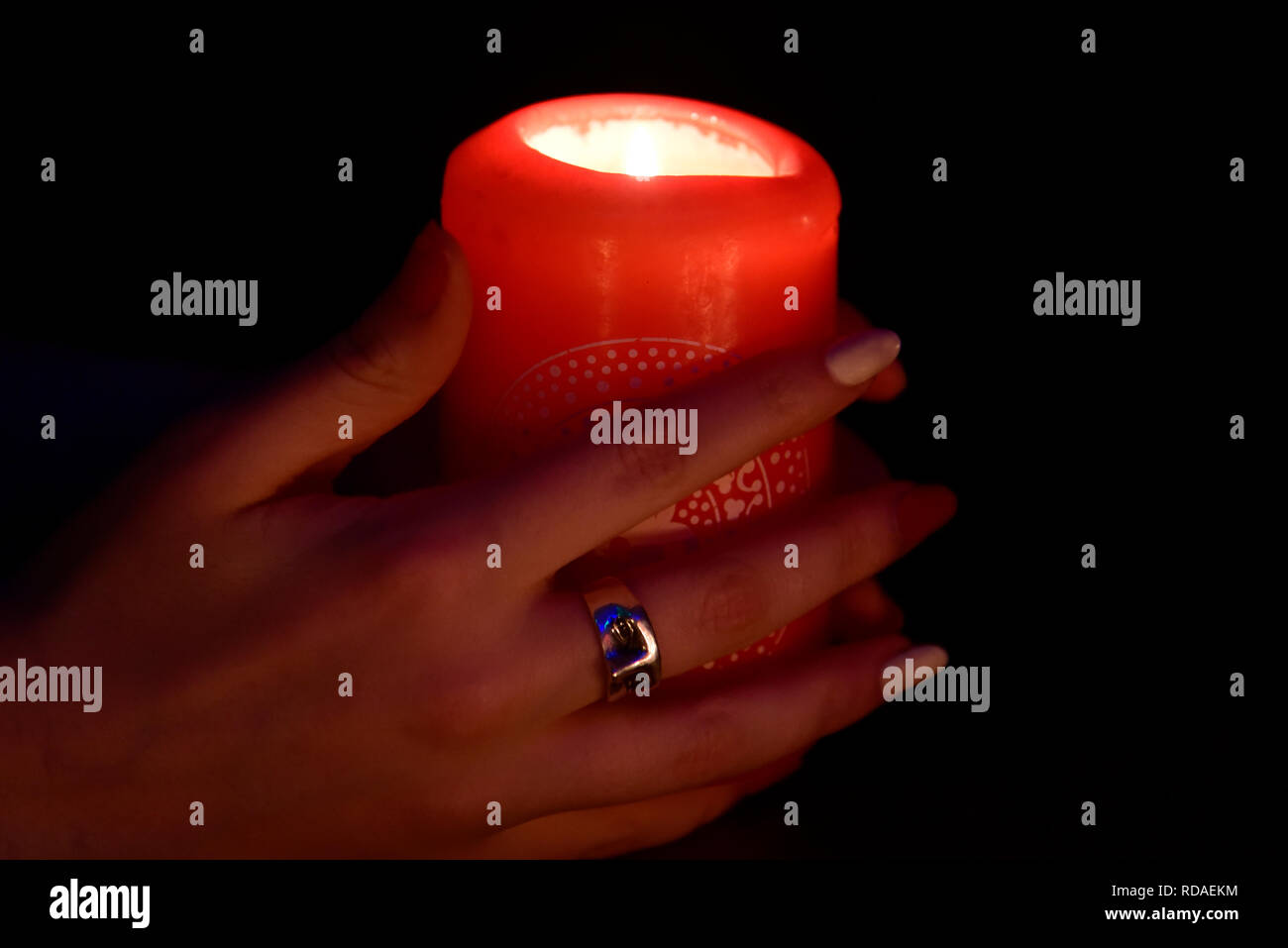 Women's hand holding a burning red candle in the dark light Stock Photo ...