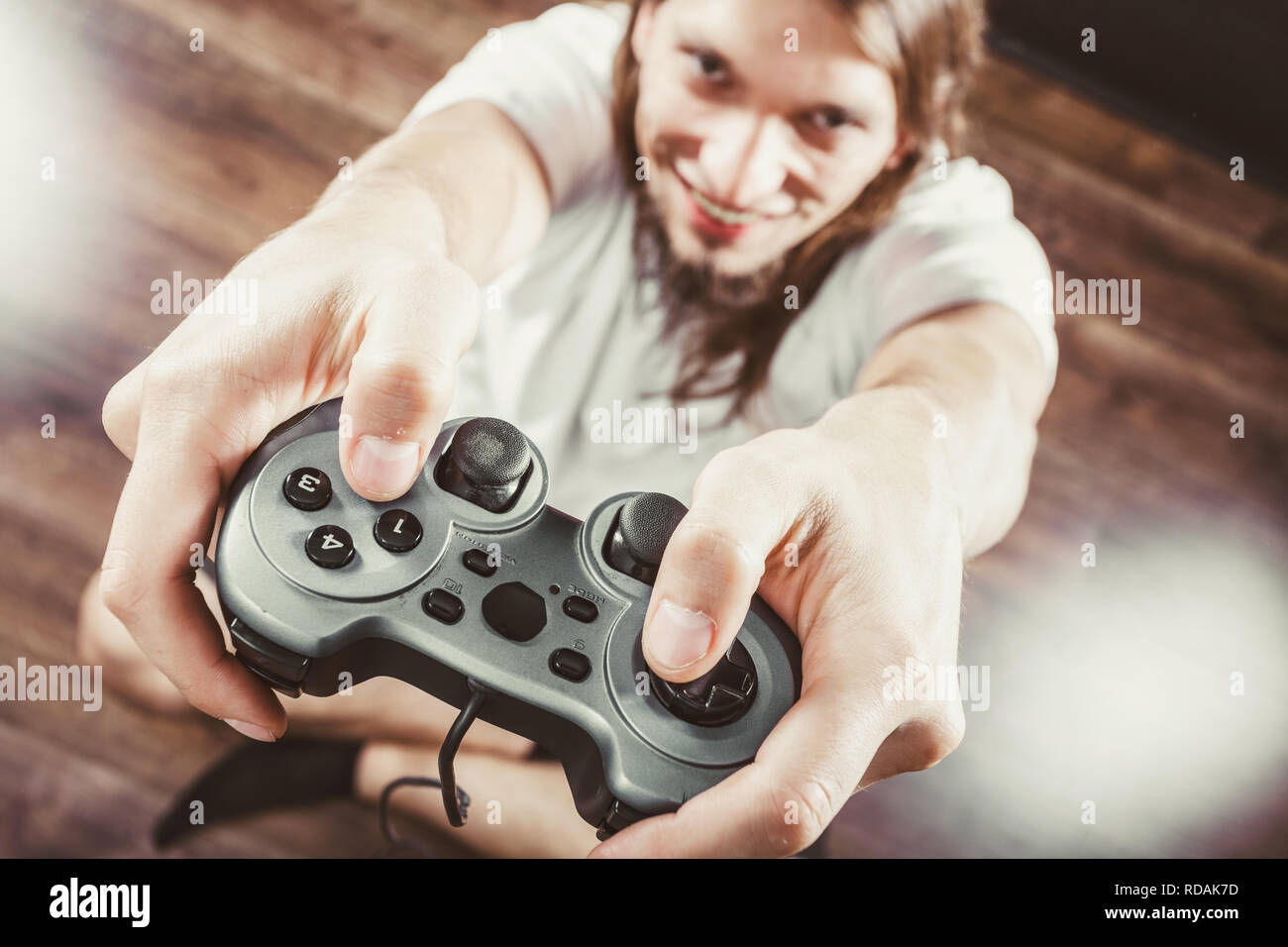 Playing games. Young smiling cheerful man play on console xbox playstation. Guy with pad ...