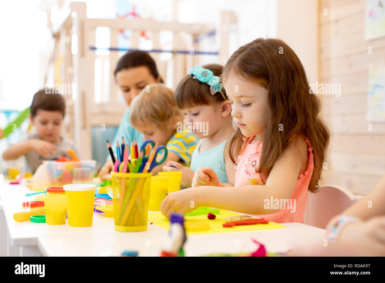 kindergarten children doing arts and crafts with teacher in day care ...